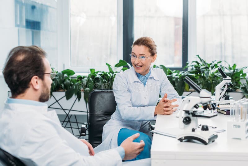 Scientists in Lab Coats and Eyeglasses Discussing Work at Workplace ...