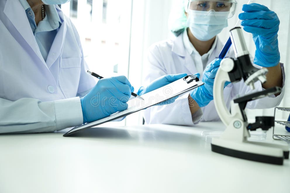 Scientists are Looking at the Microscope and Taking Notes Stock Image ...