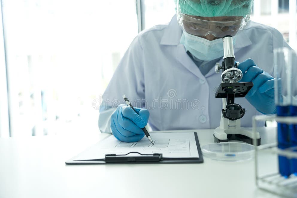 Scientists are Looking at the Microscope and Taking Notes of Scientific ...