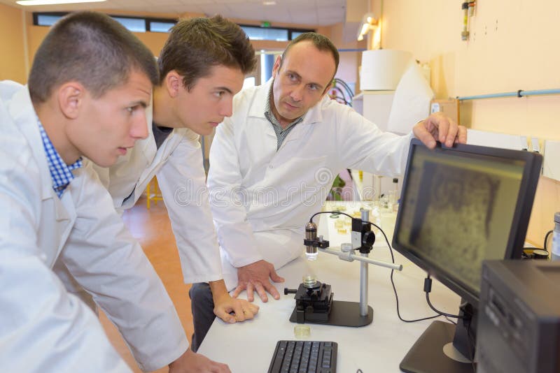Scientists Looking at Samples on Screen through Microscope Stock Photo ...