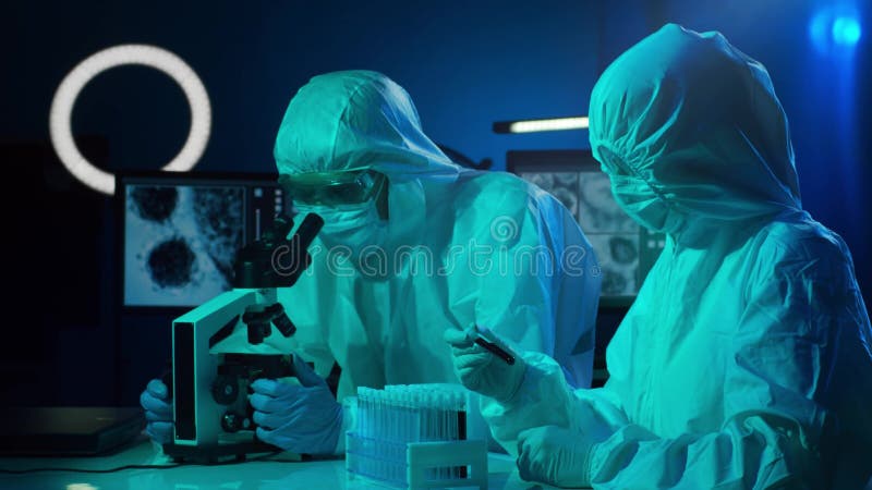Scientists in Protection Suits and Masks Working in Research Lab Using ...