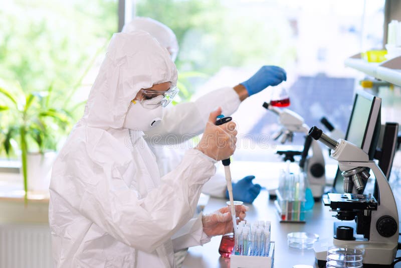 Scientists in Protection Suits and Masks Working in Research Lab Using ...