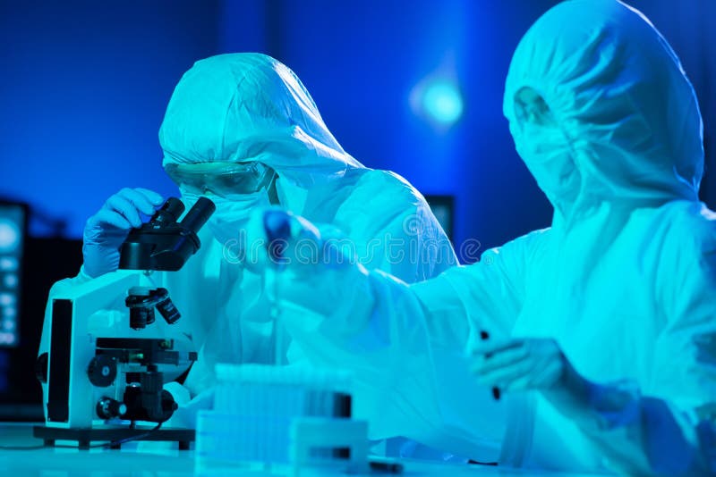 Scientists in Protection Suits and Masks Working in Research Lab Using ...