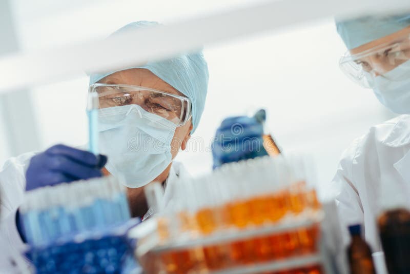 Scientists in Protective Masks Standing in Front of a Rack of Test ...