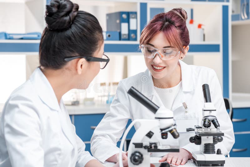 Scientists Working Together with Microscopes in Chemical Lab Stock ...