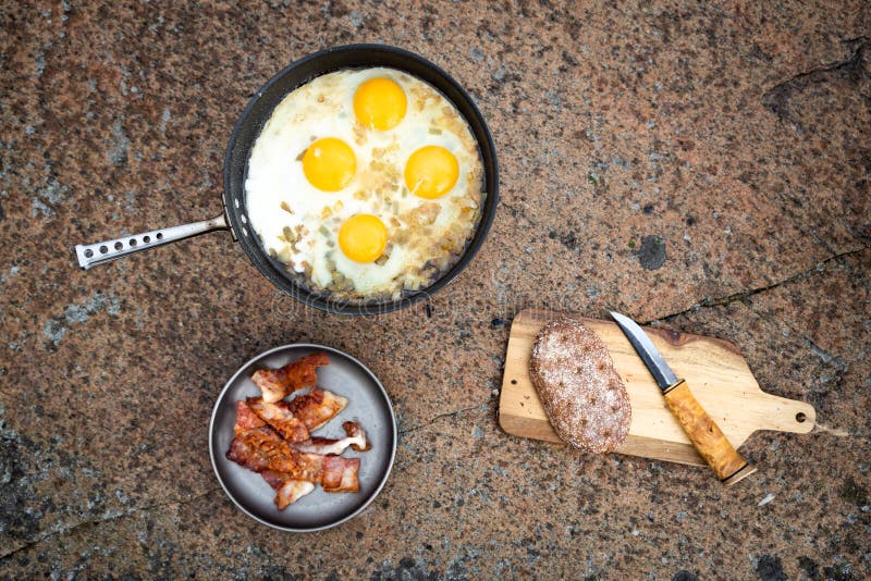 Cooking Breakfast Eggs and Bacon on Camping Stove. Camping Food. Eggs ...