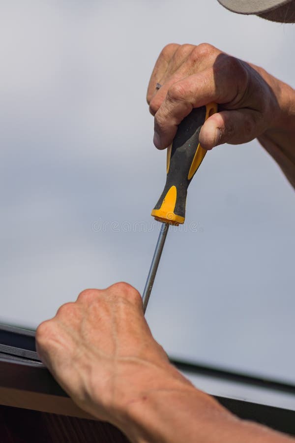 Screwdriver in Males Hands. Worker with a Hand Tool Assembling Metal ...