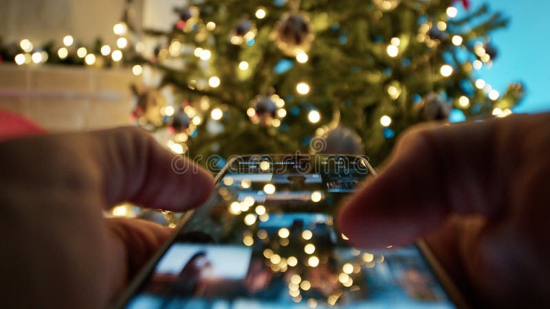 Scrolling on Smartphone Under Christmas Tree Stock Photo - Image of ...
