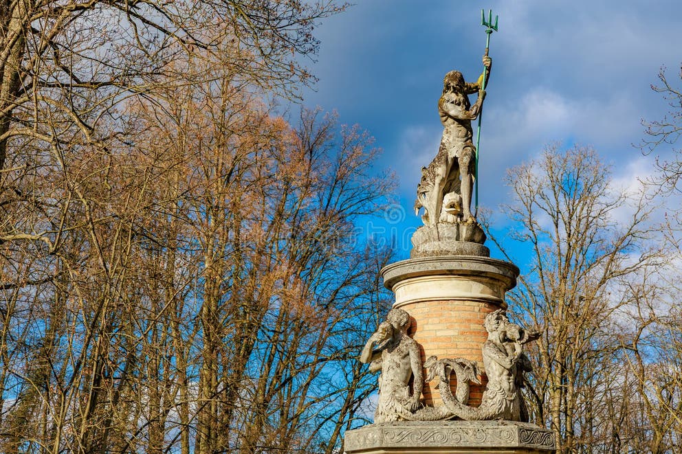 Sculpture of Neptune with Trident in Leafless Park Setting Against Blue ...