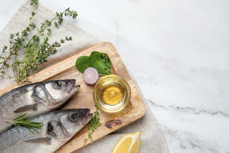 Sea Bass Fish and Ingredients on White Marble Table, Flat Lay. Space ...