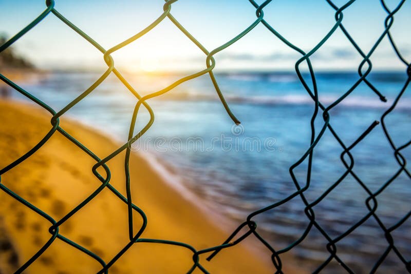 Sea and Beach at Sunset Behind Ripped Wire Fence Stock Photo - Image of ...