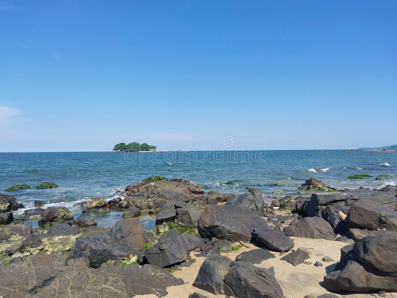 Seaside with Several Rocks and a Small Island in the Background. Stock ...