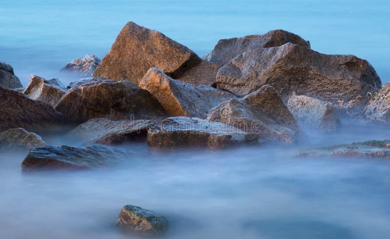 Sea rocks in mist at dusk stock image. Image of shore - 69966669