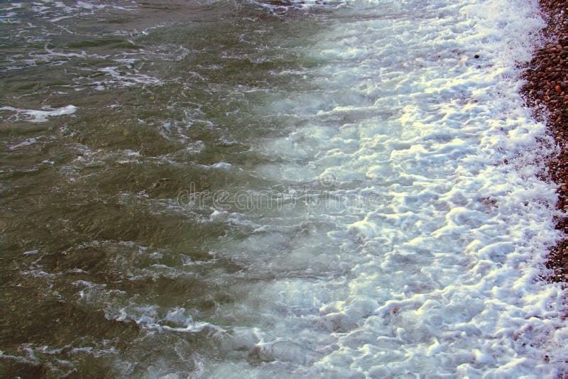 Sea Rolling and Receding Water in Rays of Setting Sun. Stock Image ...