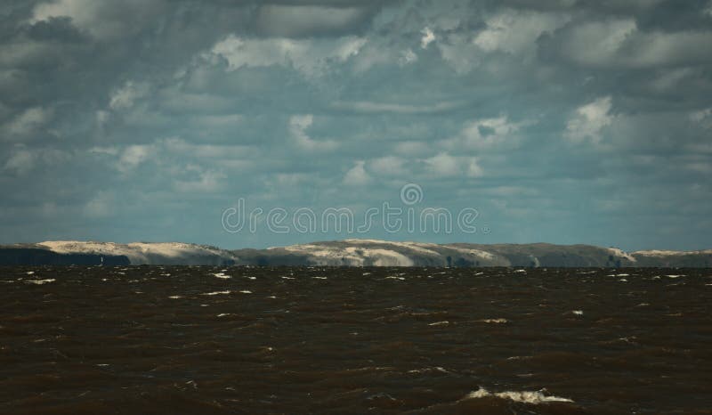 Sea Water with Waves and Land with Sand Dunes in Horizon with Clouds ...