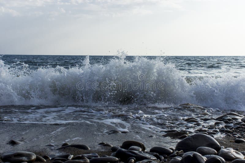 Sea wave on a stone beach stock photo. Image of cloud - 121809820