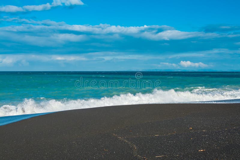 Sea Waves Breaking on a Black Sand Beach. Distant Line of Cargo Ships ...