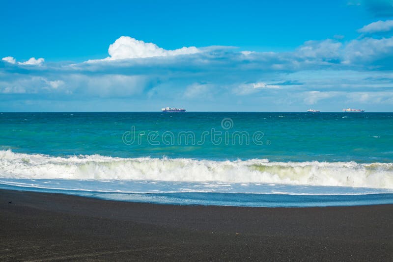Sea Waves Breaking on a Black Sand of an Empty Beach. Distant Cargo ...