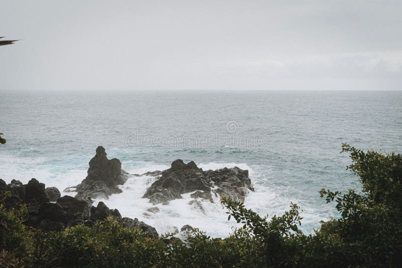 Sea Waves Splash Over the Rocks on the Shore with a Gray Sky in the ...