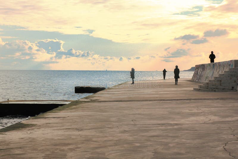 Seafront at Sunset. Several Figures on the Background of the Sea ...