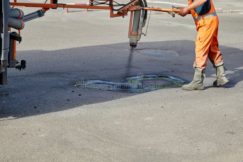 Road Worker Repairing Asphalt Coating, Using a Manipulator. Pitching ...