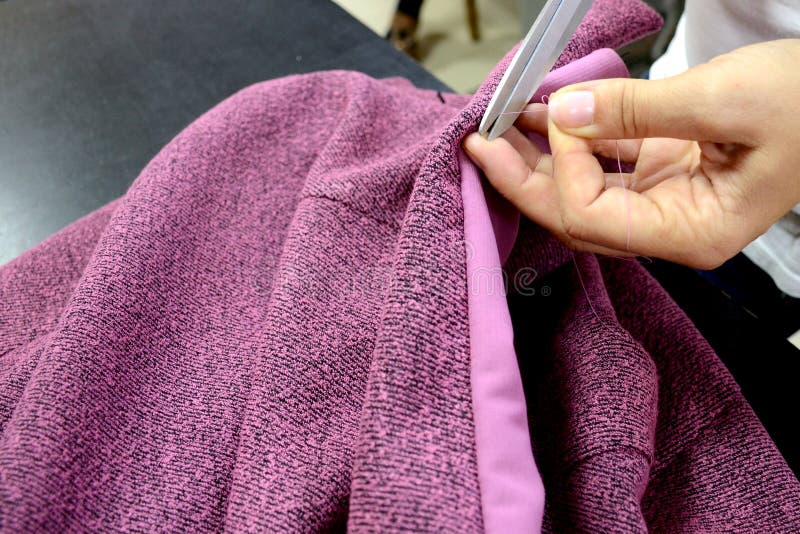 A Seamstress Cuts a Thread on a Pink Knit Fabric with Scissors. Cutting ...