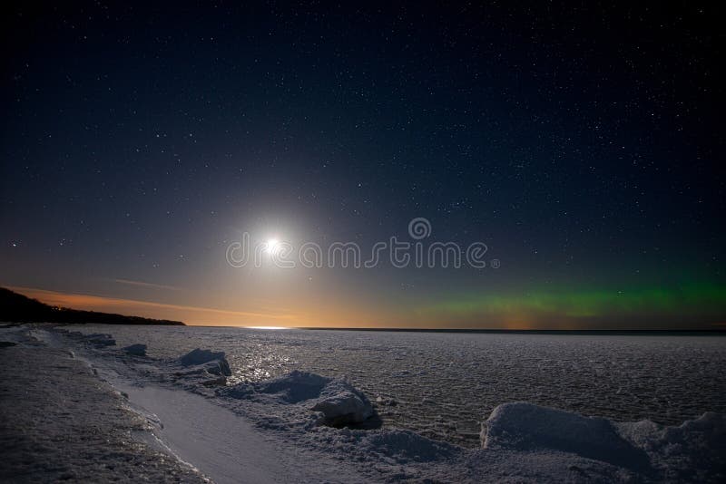Seashore Covered with Ice Under a Starry Sky with Moon and Northern ...