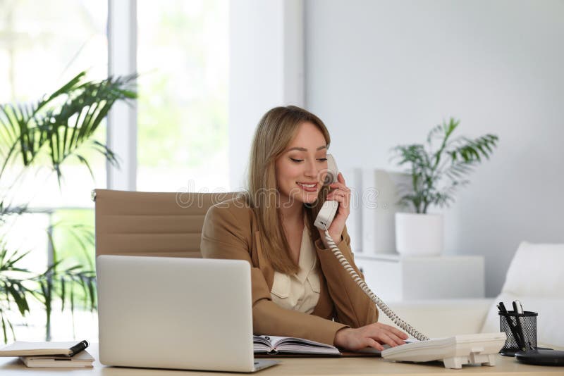 Secretary Talking on Phone at Table in Office Stock Photo - Image of ...