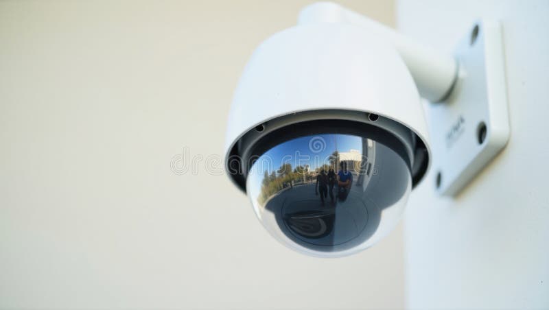Security Camera Mounted on a Wall Reflecting a Bustling Outdoor Setting ...