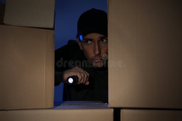 Security Guard with Flashlight Looking through Pile of Cardboard Boxes ...