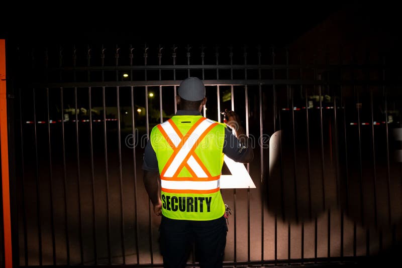 Security Person Standing at the Fence at Night, Shot from Back Stock ...