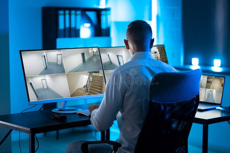Security System Operator Looking at CCTV Footage at Desk Stock Photo ...