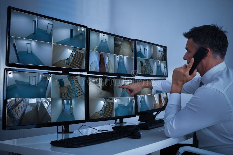 Security System Operator Looking at CCTV Footage at Desk Stock Photo ...