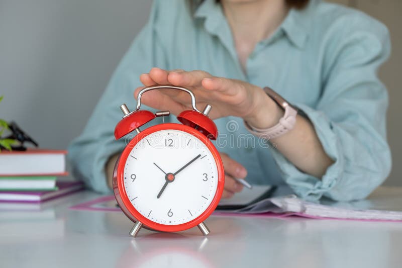 Selective Focus of an Alarm Clock on a Table Next To a Person Using a ...