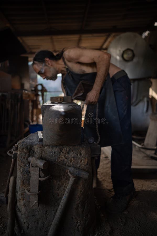 Selective Focus on an Anvil with a Blacksmith in the Background in a ...