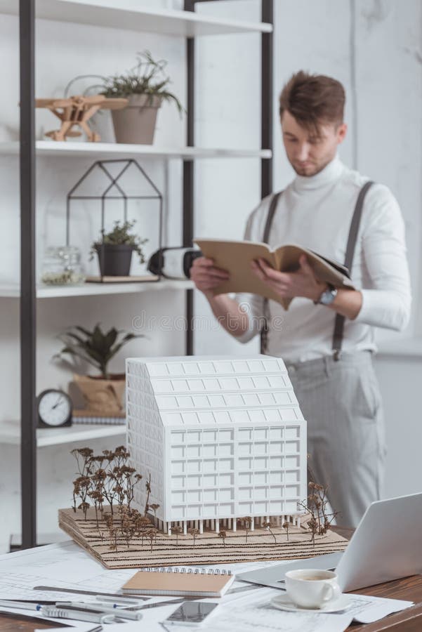Selective Focus of Architect Reading Magazine and Building Model at ...