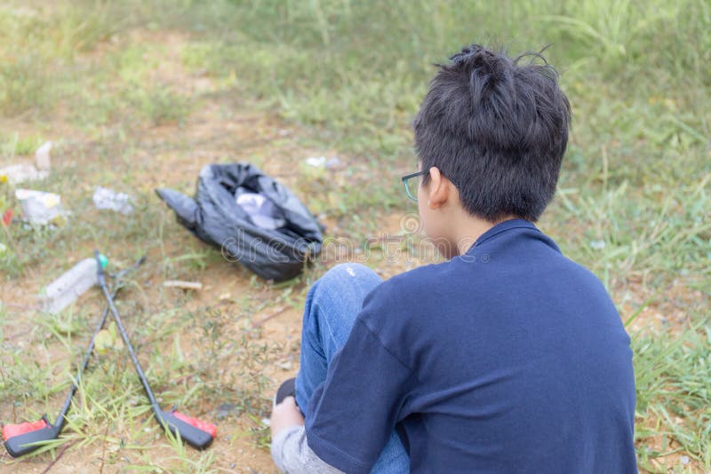 Selective Focus of Boy Collecting Garbage on a Meadow on Evening Day ...