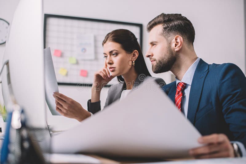 Focus of Computer Systems Analysts Looking at Papers Near Computer on ...