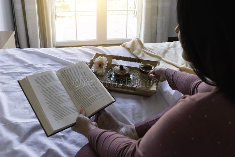 Beautiful Girl Reading a Book Relaxedly while Having Breakfast in Bed ...
