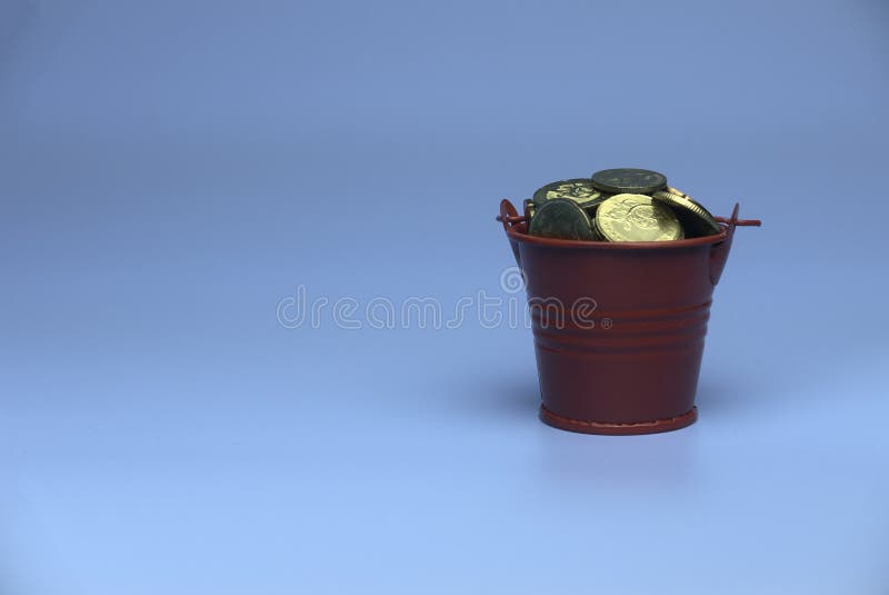 Selective Focus of Red Bucket Full with Gold Coins Isolated on a Blue ...