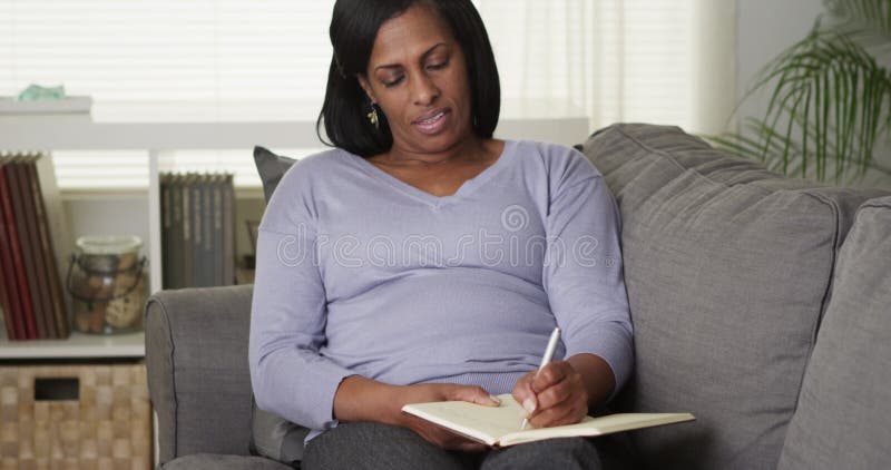 Senior African Woman Writing in Journal on Couch Stock Video - Video of ...
