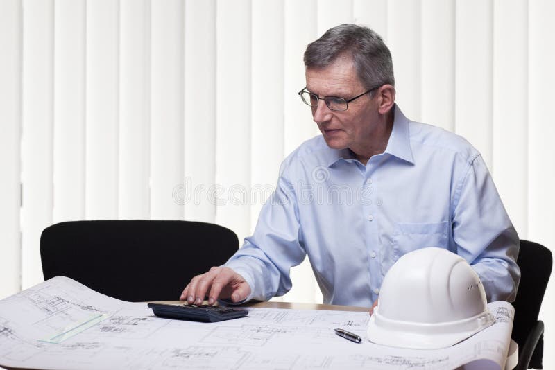 Senior Architect or Engineer Calculating a Project in an White Office ...