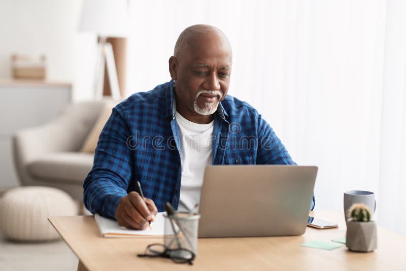 Senior Black Man Using Laptop Taking Notes Working at Home Stock Photo ...