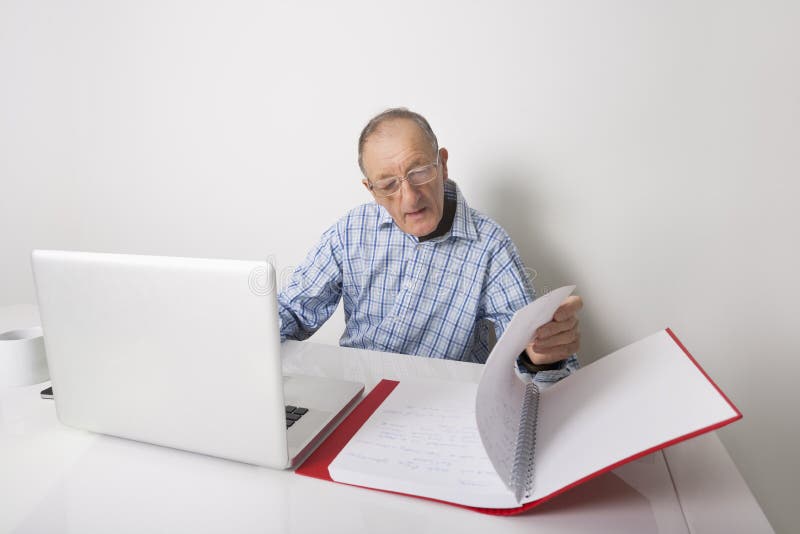 Senior Businessman Using Laptop while Reading File at Office Desk Stock ...