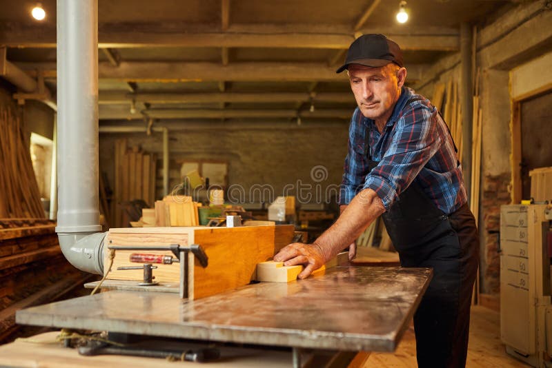 Senior Carpenter in Uniform Works on a Woodworking Machine at the ...