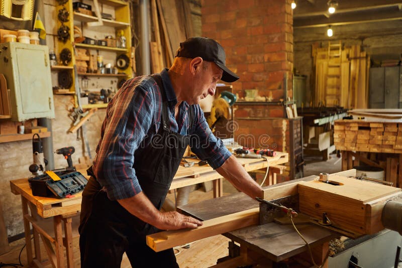 Senior Carpenter in Uniform Works on a Woodworking Machine at the ...