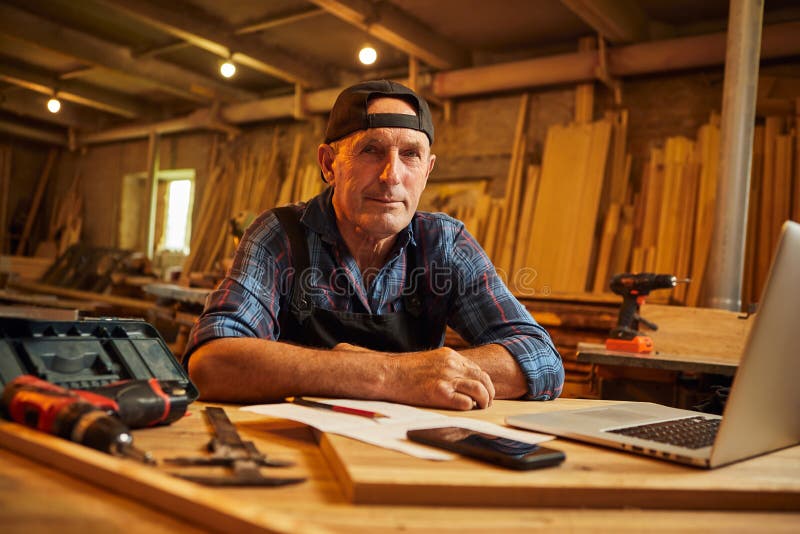 Senior Carpenter Works on the Computer and Look at the Camera in the ...
