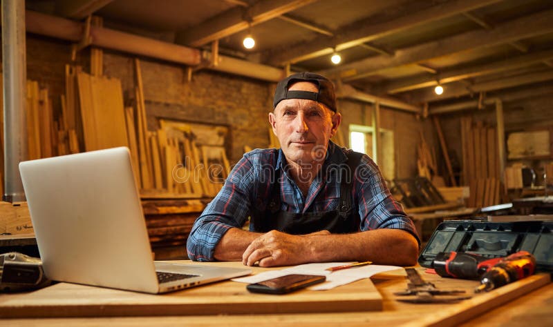 Senior Carpenter Works on the Computer and Look at the Camera in the ...