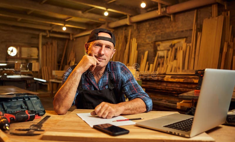 Senior Carpenter Works on the Computer and Look at the Camera in the ...