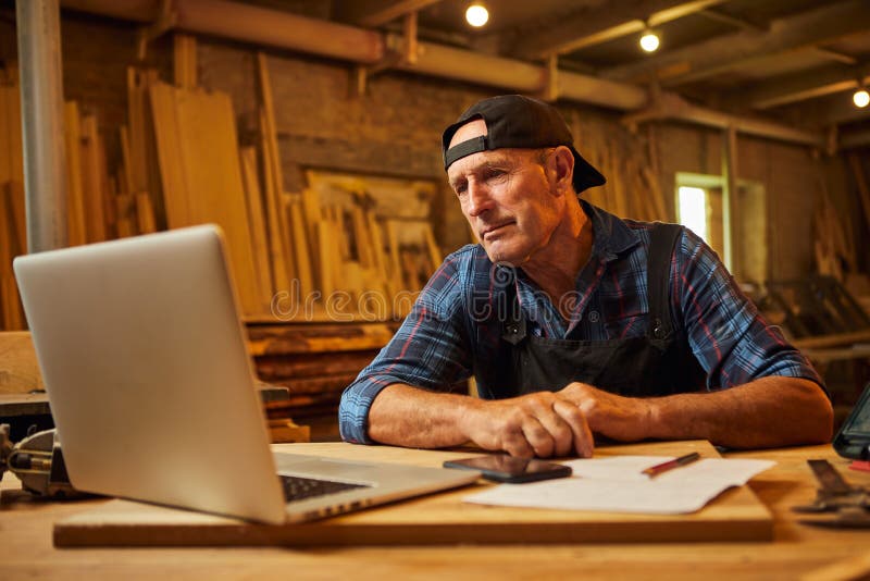 Senior Carpenter Works on the Computer in the Workshop Stock Photo ...